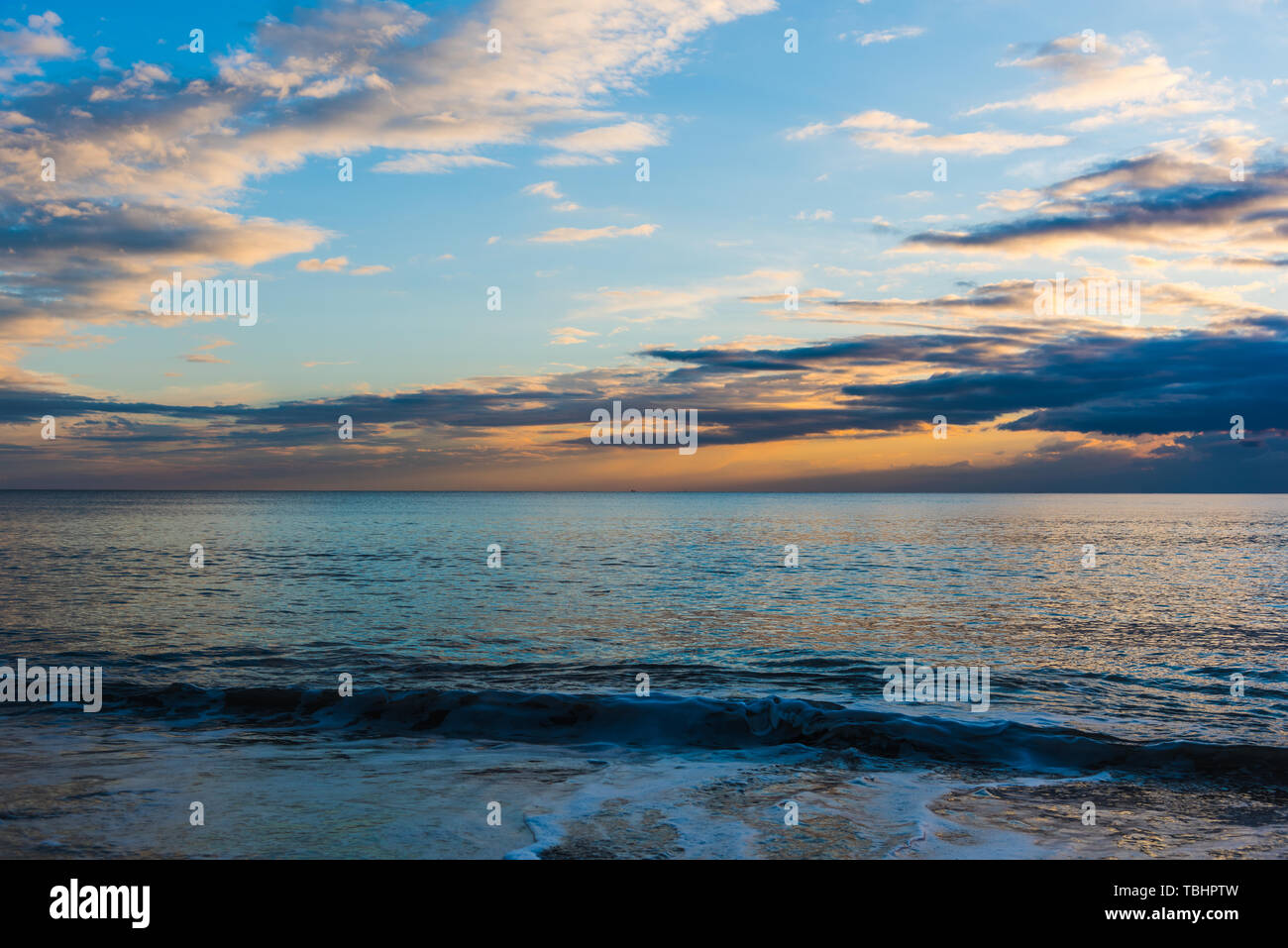 Sand and rocks by the sea at sunset Stock Photo - Alamy