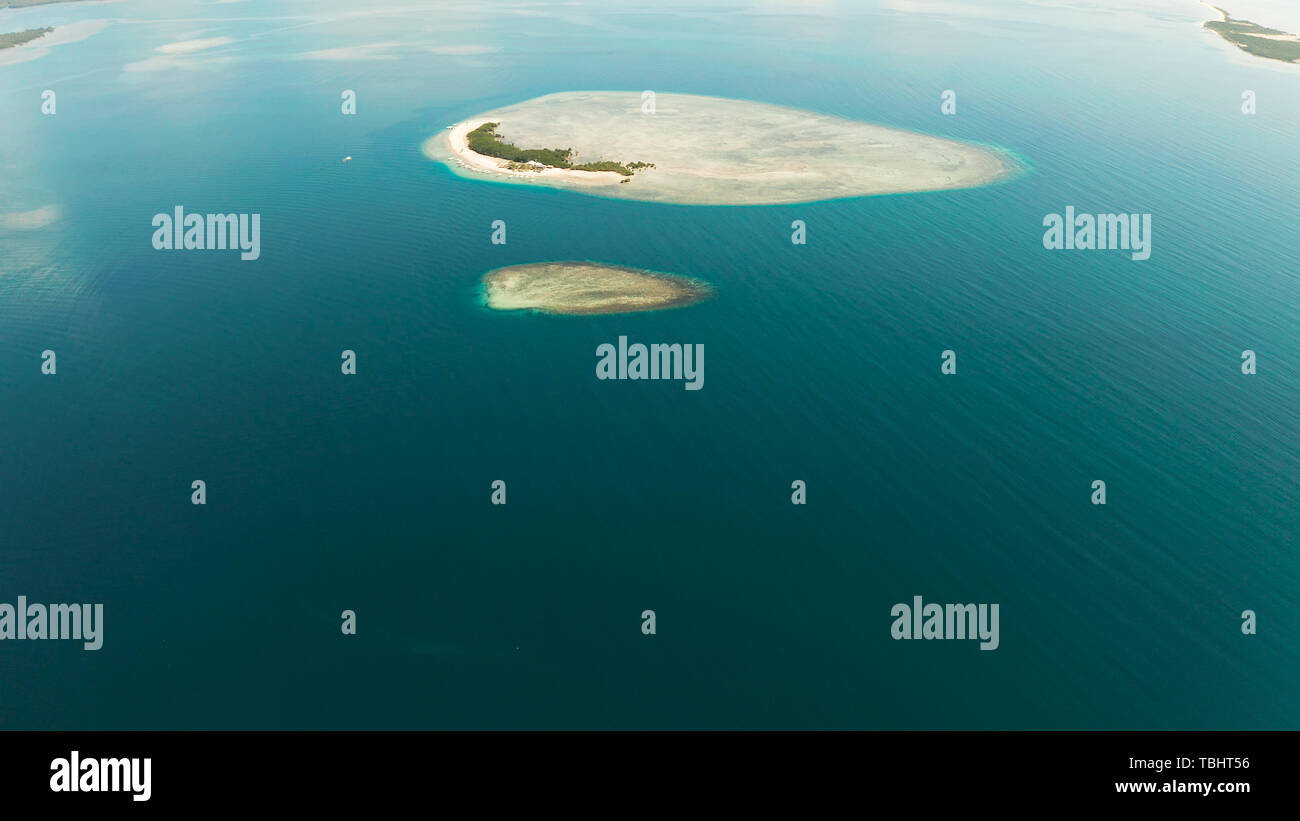 Tropical island and sandy beach with tourists surrounded by coral reef ...