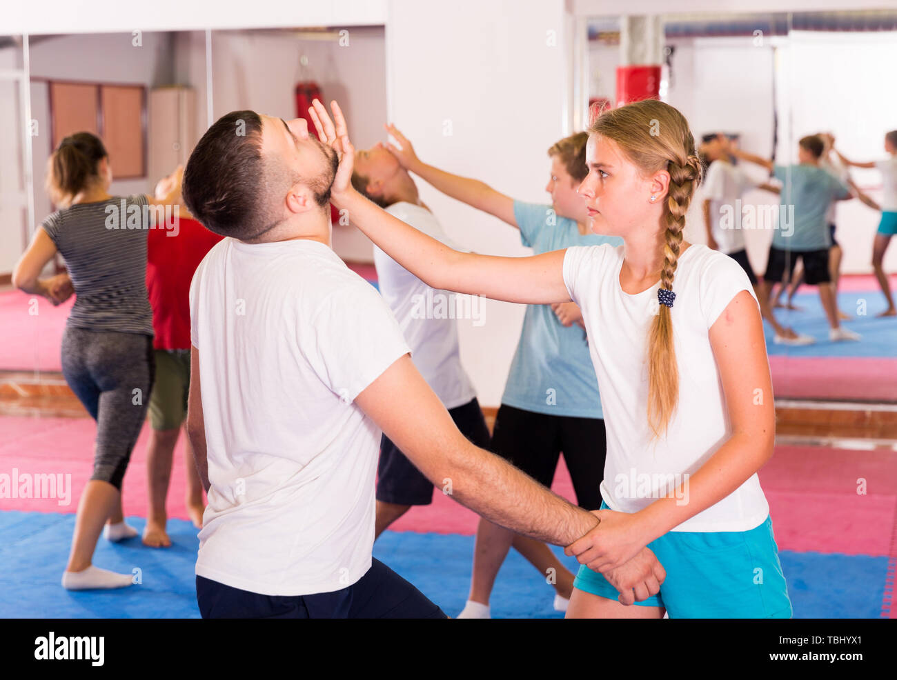 Adult and teen people practicing self defence technique in pairs at gym ...