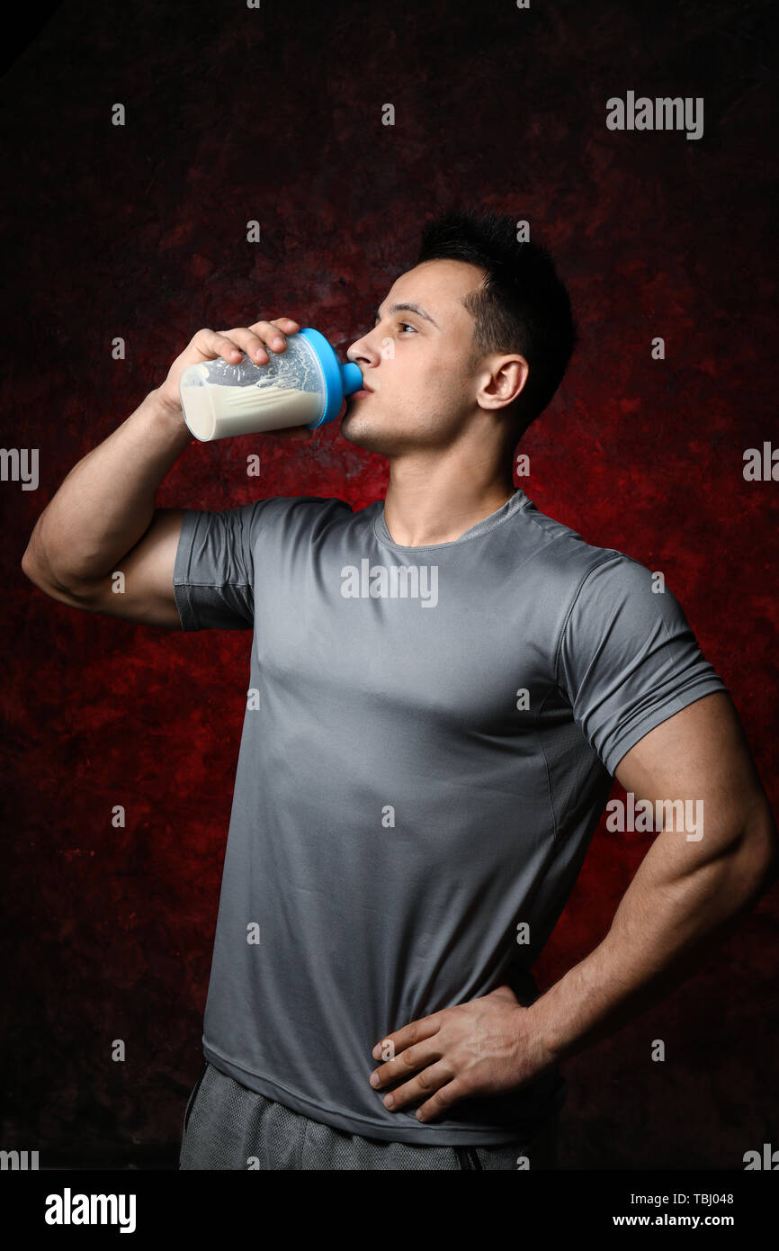 Sporty man drinking protein shake on dark background Stock Photo - Alamy