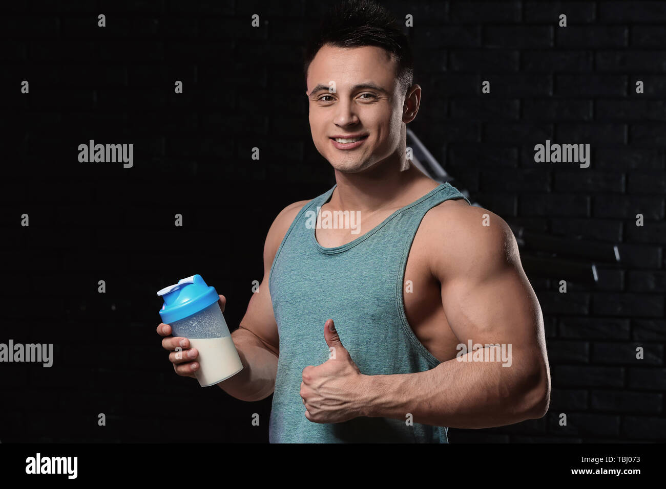 Sporty man with protein shake on dark background Stock Photo - Alamy