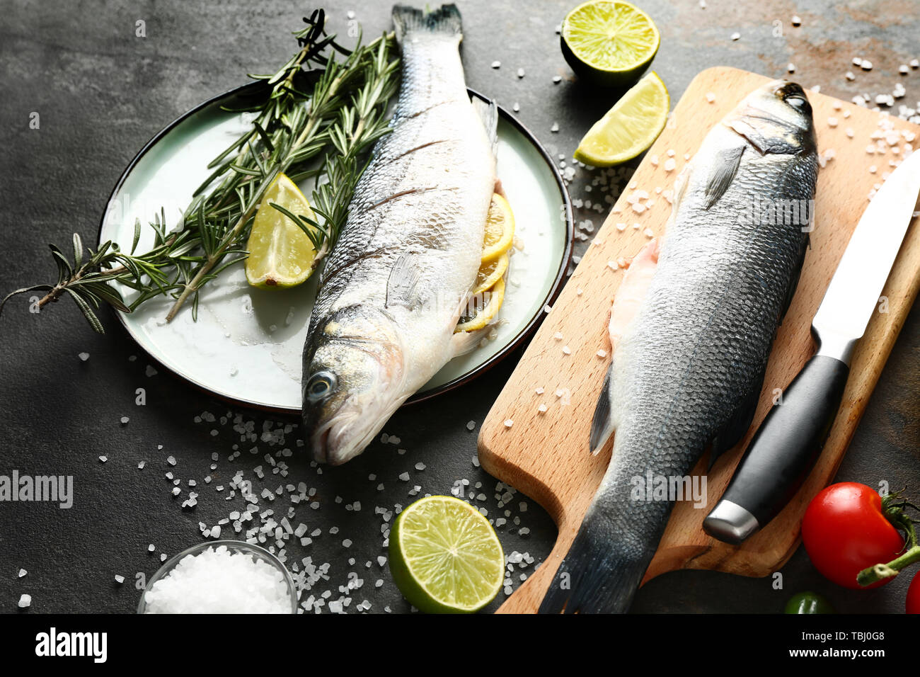 Preparing of tasty fresh fish on dark table Stock Photo - Alamy