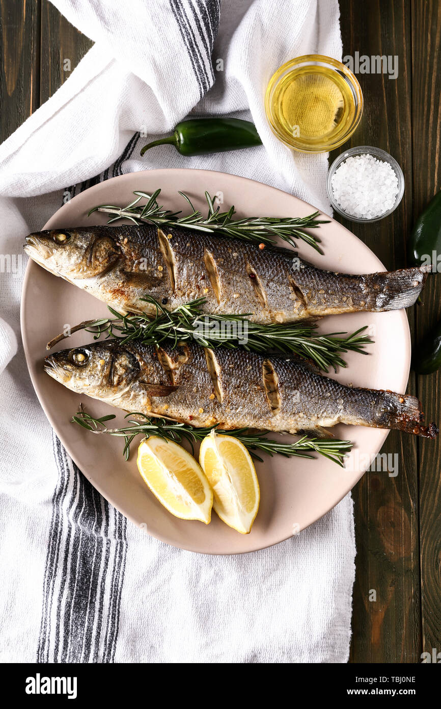 Plate with tasty cooked fish on wooden table Stock Photo - Alamy