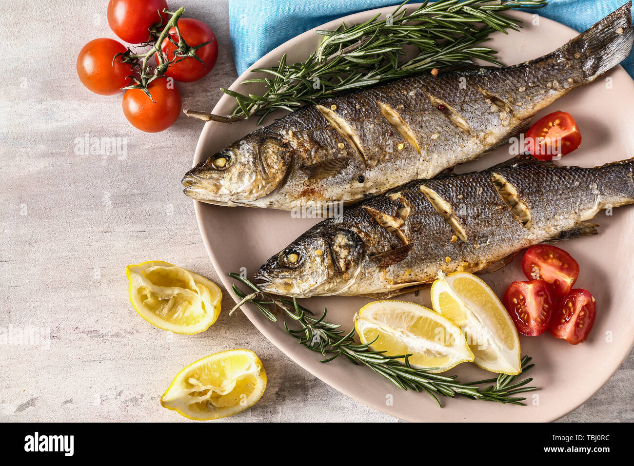 Plate with tasty cooked fish on light table Stock Photo - Alamy