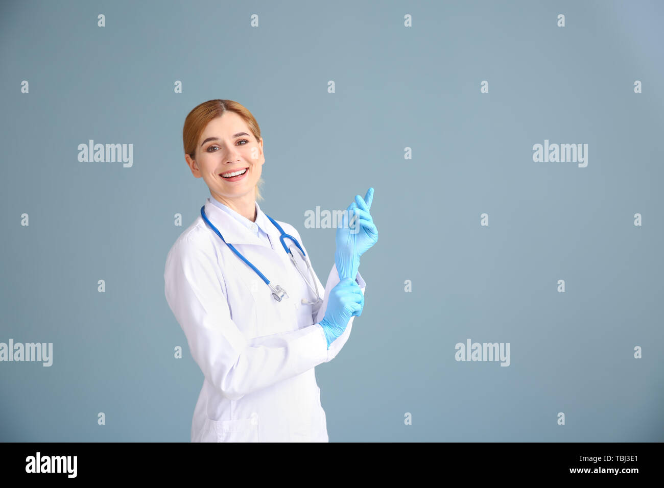Portrait of beautiful gynecologist on grey background Stock Photo - Alamy