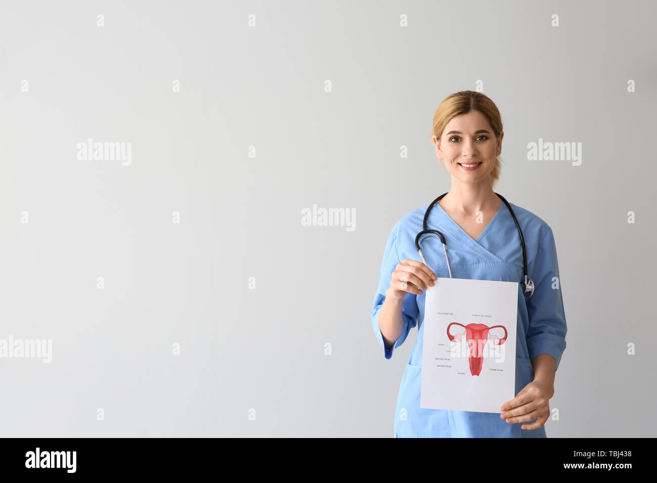 Portrait of beautiful gynecologist on light background Stock Photo - Alamy