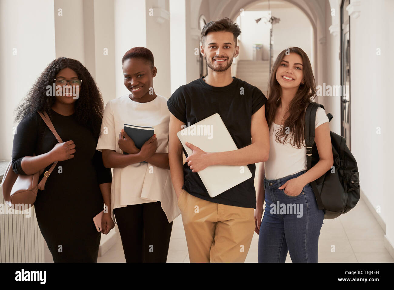 Front view of four happy students with backpacks going to lecture ...
