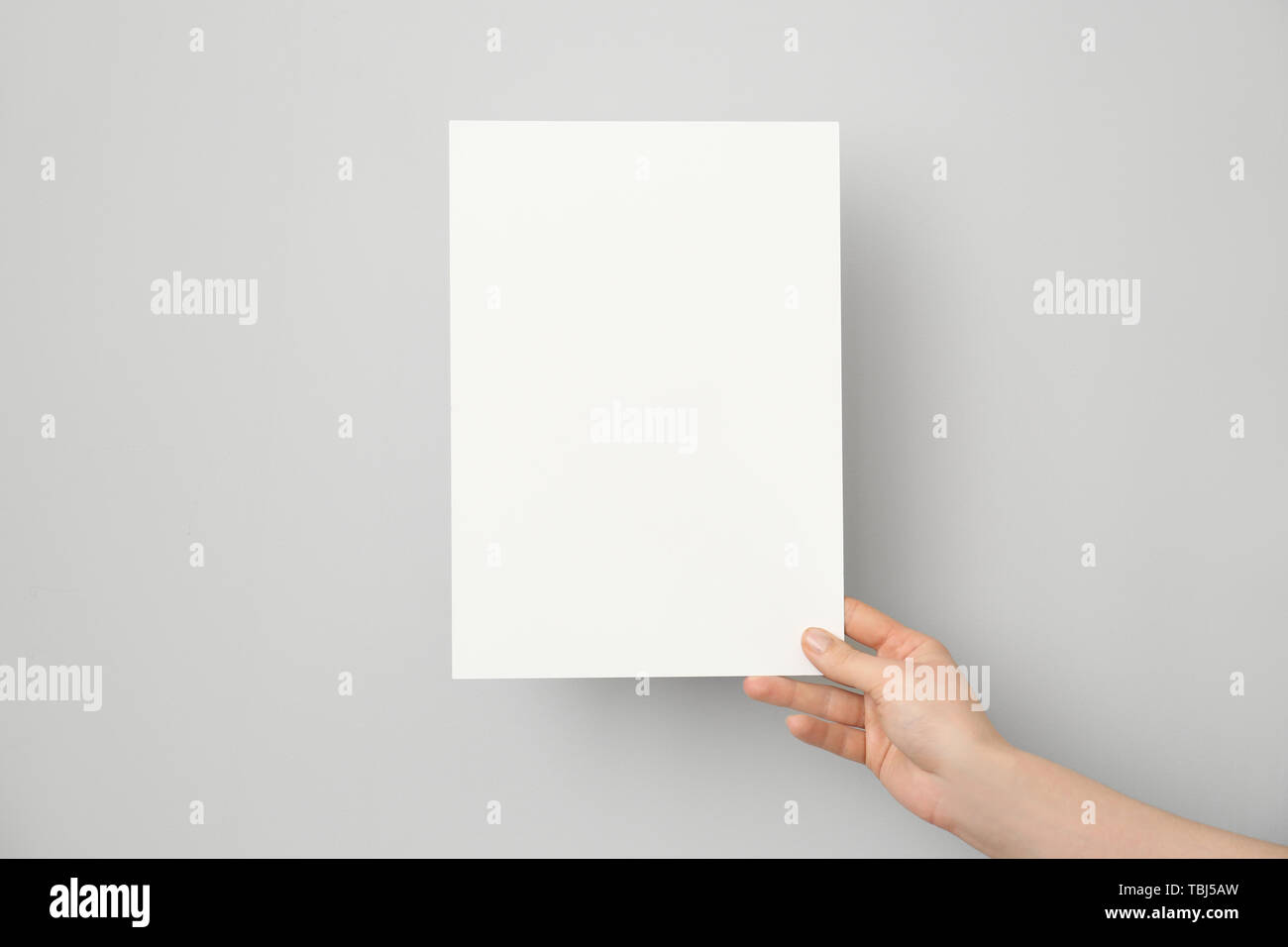 Female hand with blank invitation card on light background Stock Photo ...