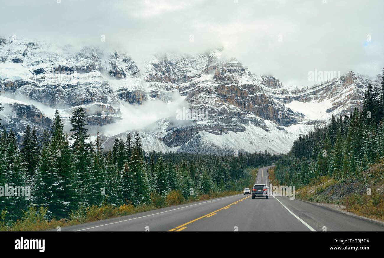 Highway with snow capped mountain forest and car in Banff National Park ...