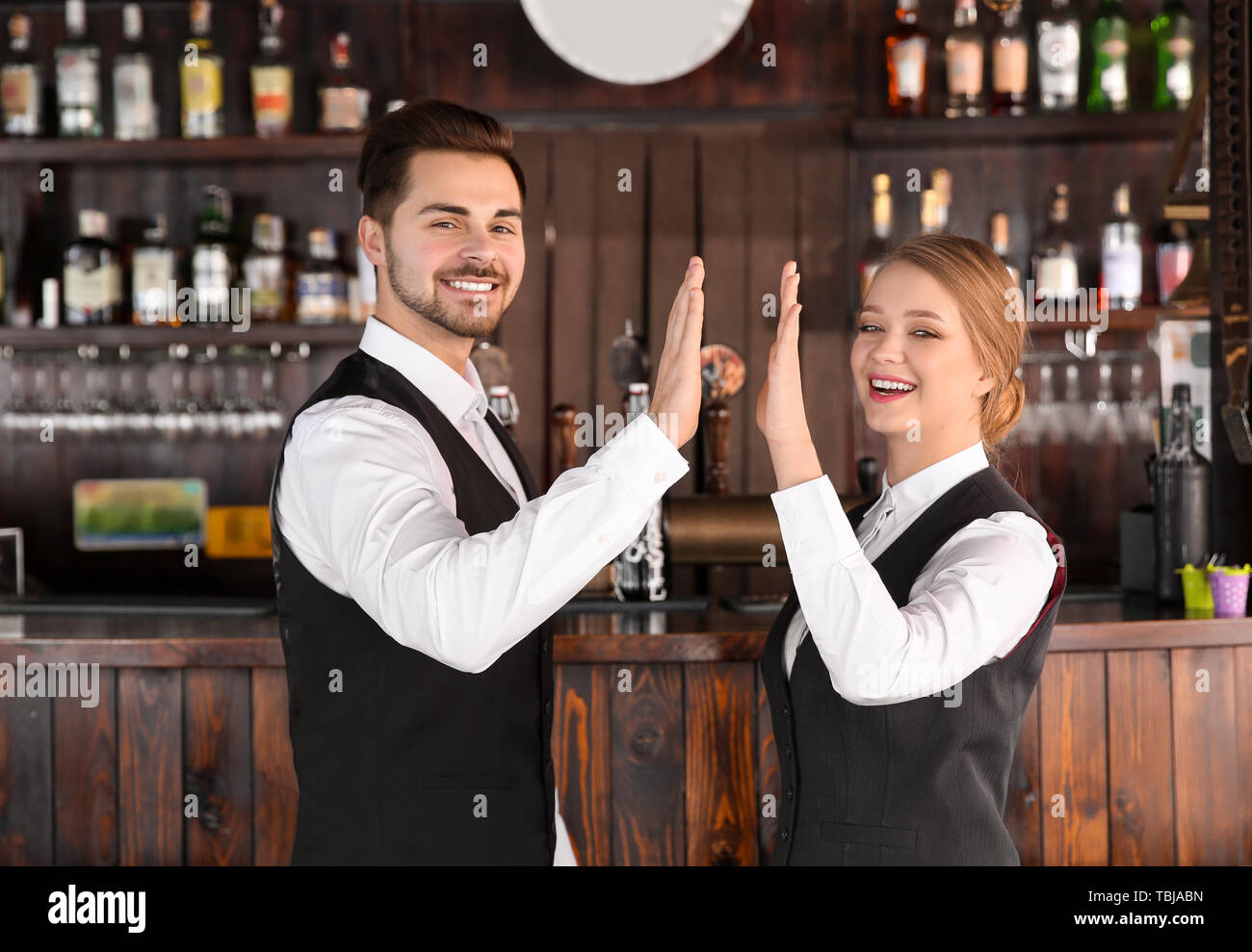 Young waiters giving each other high-five in restaurant Stock Photo - Alamy