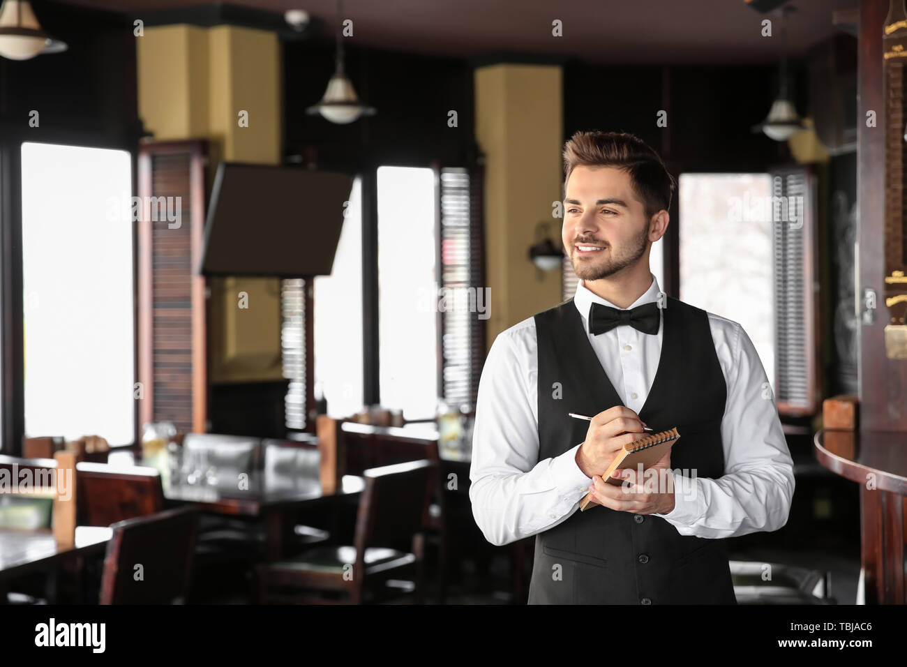 Young male waiter with notebook in restaurant Stock Photo - Alamy