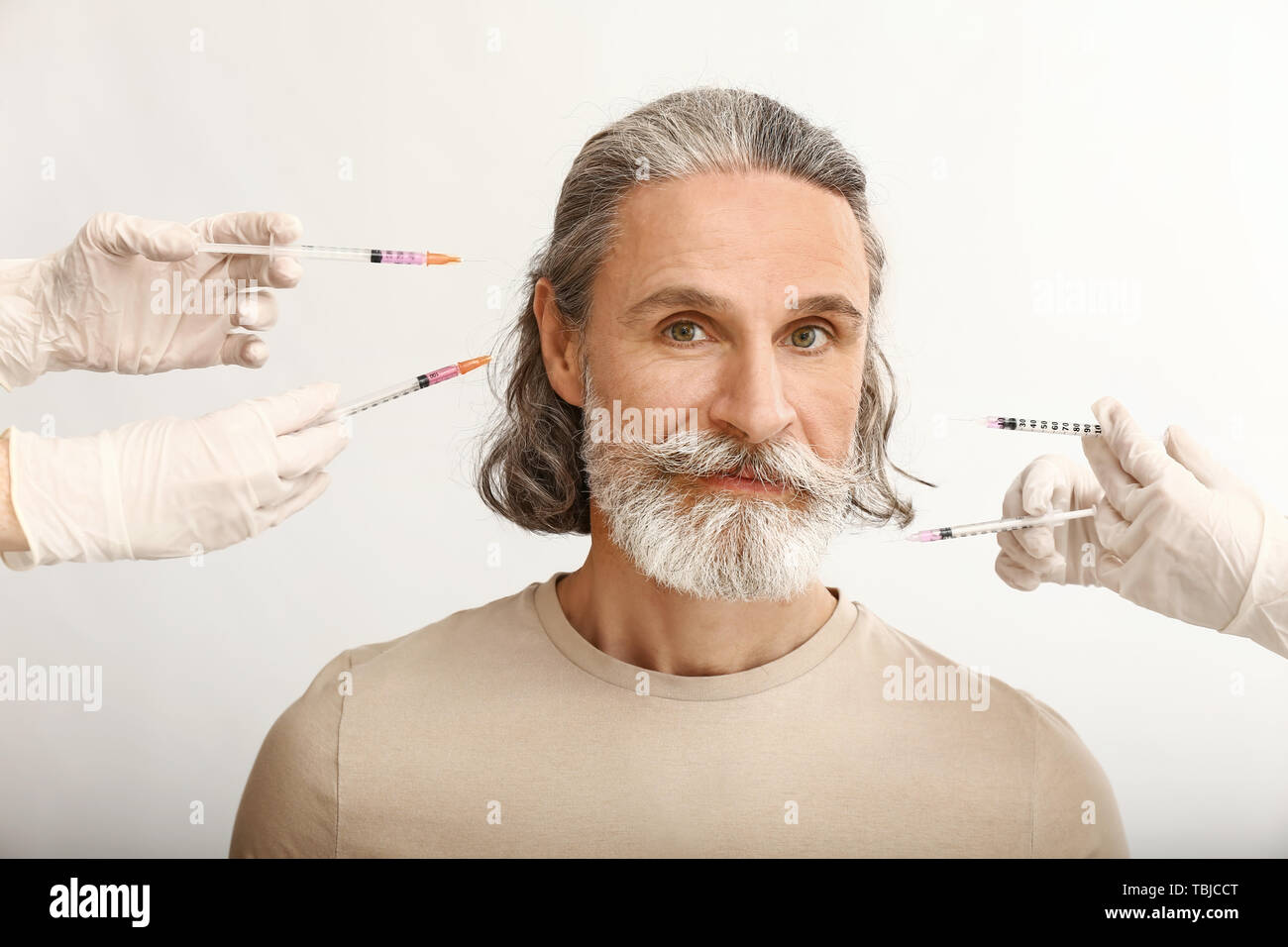 Mature man and hands holding syringes for anti-aging injections on ...