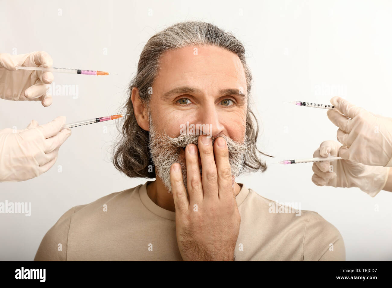 Mature man and hands holding syringes for anti-aging injections on ...