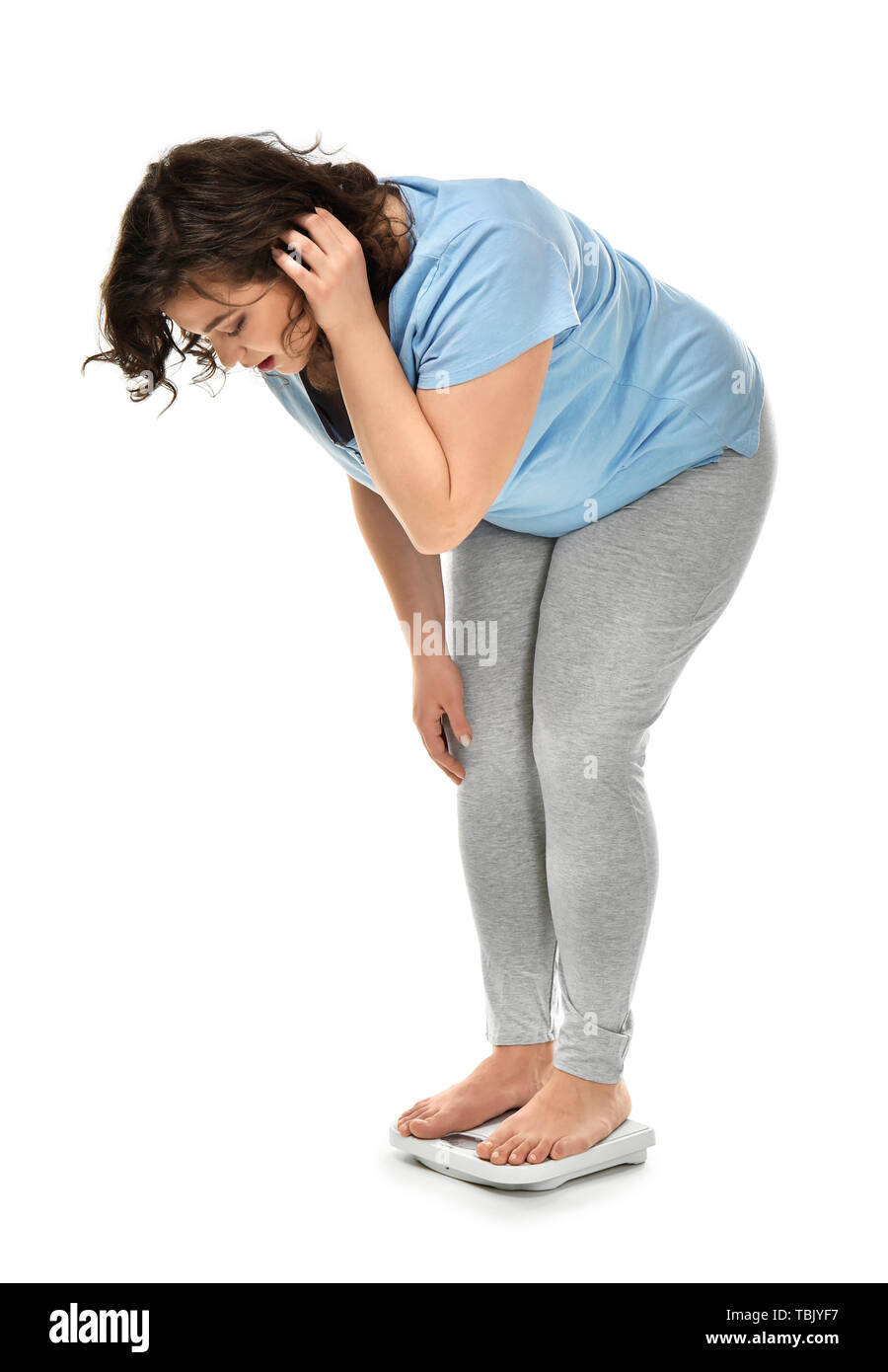 Shocked overweight woman on scales against white background Stock Photo ...