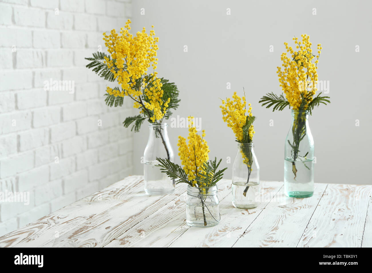 Glassware with beautiful mimosa flowers on white table in room Stock ...