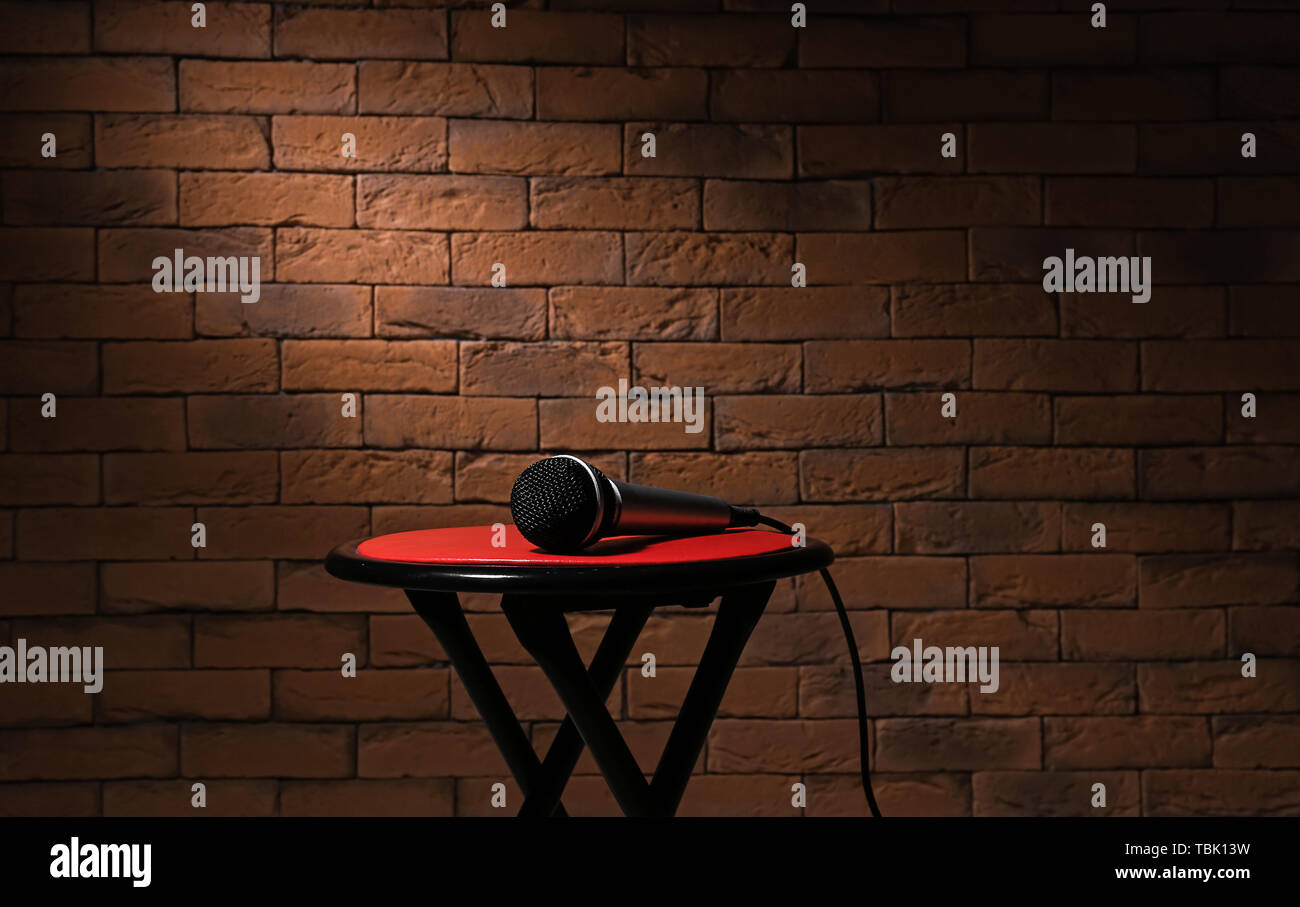 Modern microphone on stool against brick background Stock Photo - Alamy