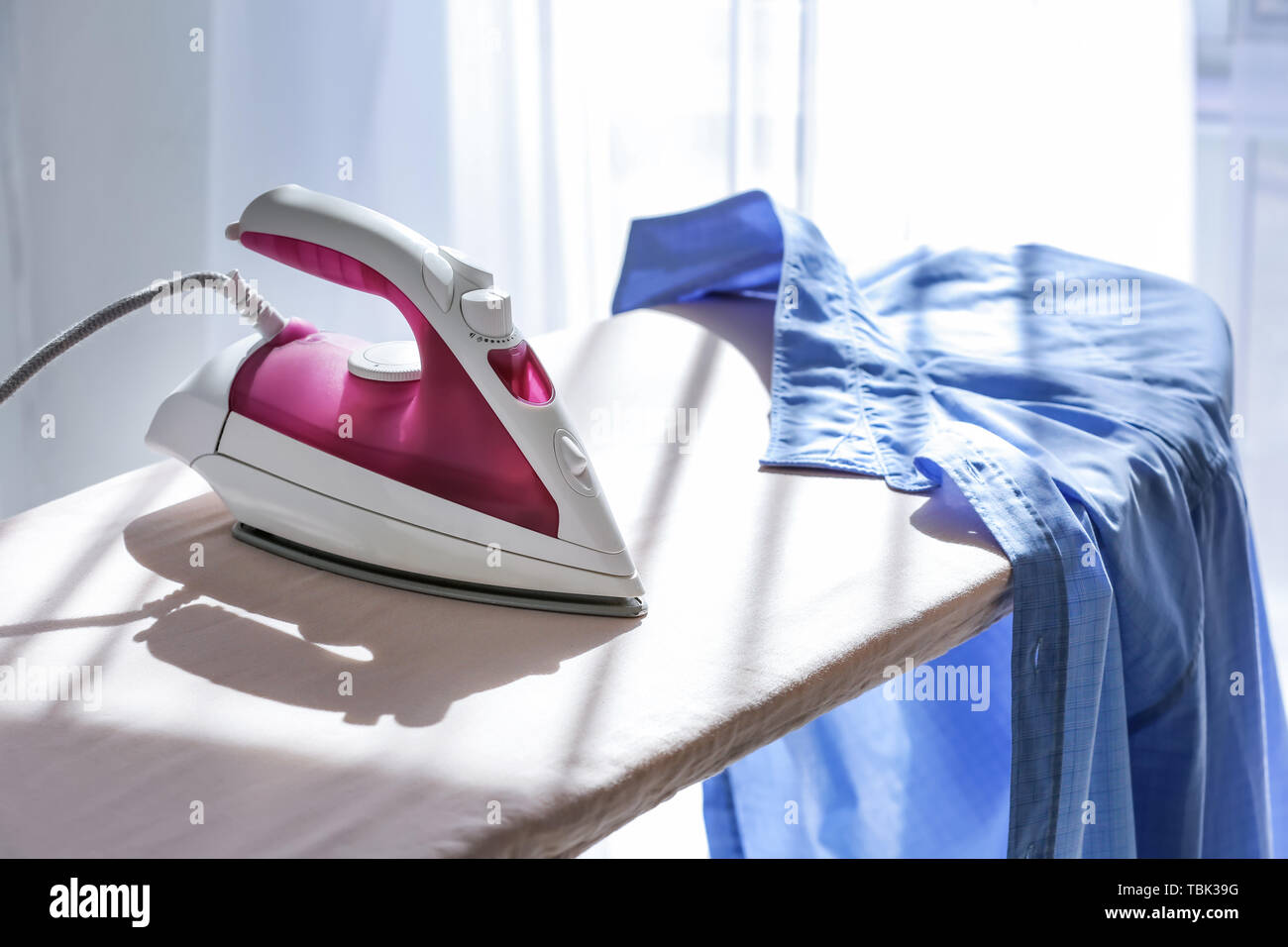 Modern iron and clothes on board Stock Photo - Alamy
