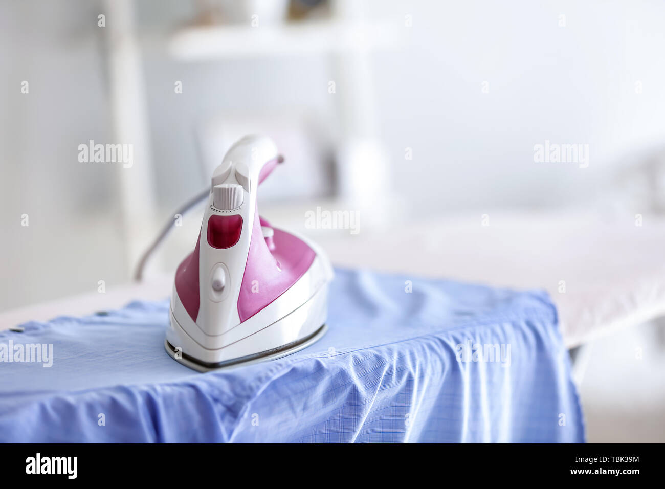 Modern iron and clothes on board Stock Photo - Alamy