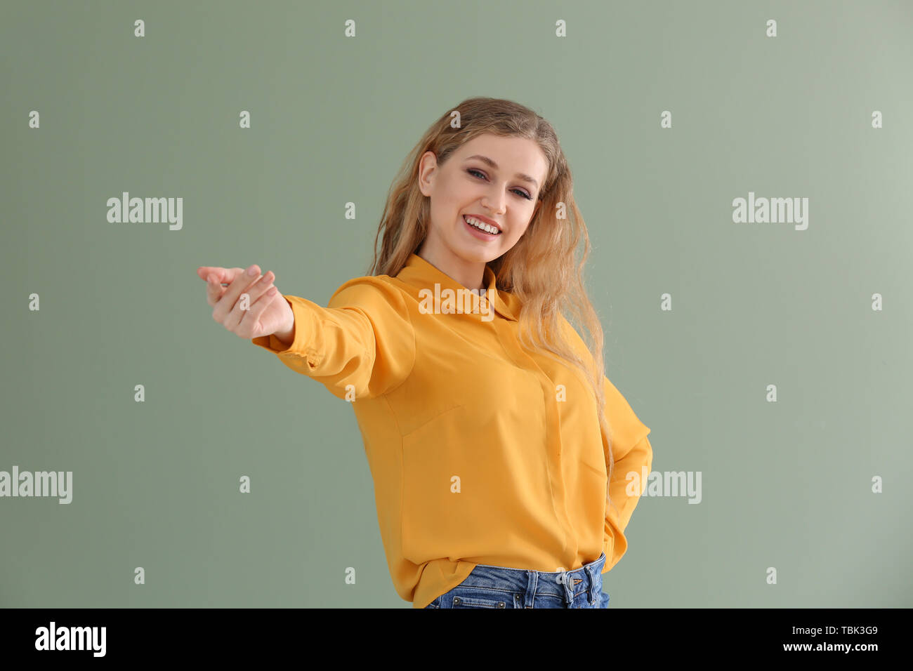 Beautiful young woman inviting viewer against color background Stock ...
