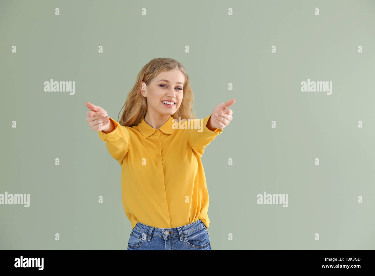 Beautiful young woman inviting viewer against color background Stock ...