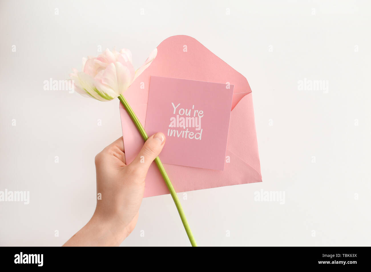 Female hand with invitation and flower on white background Stock Photo ...