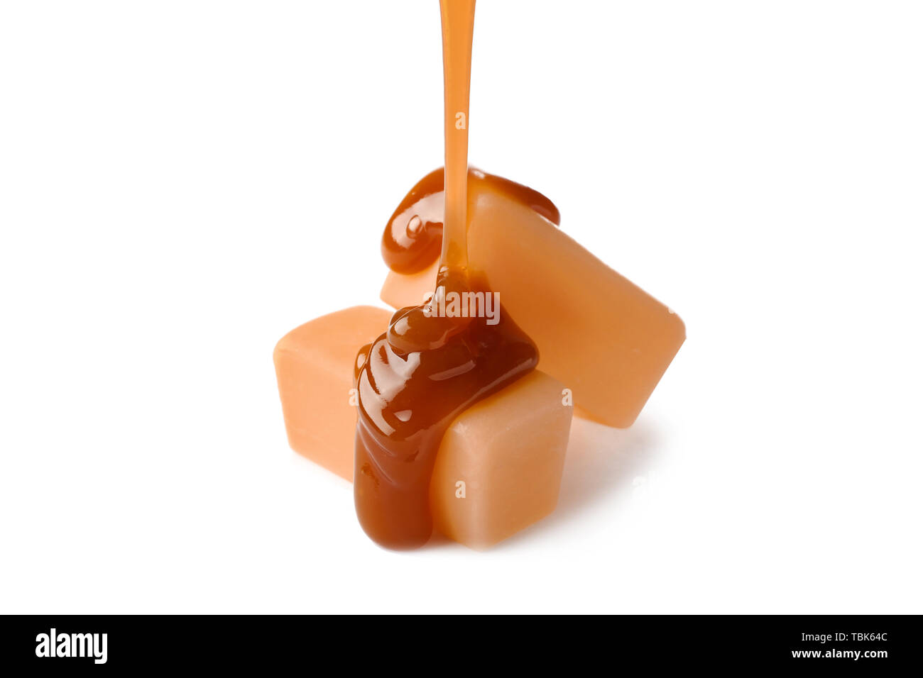 Pouring of liquid caramel onto candies on white background Stock Photo ...