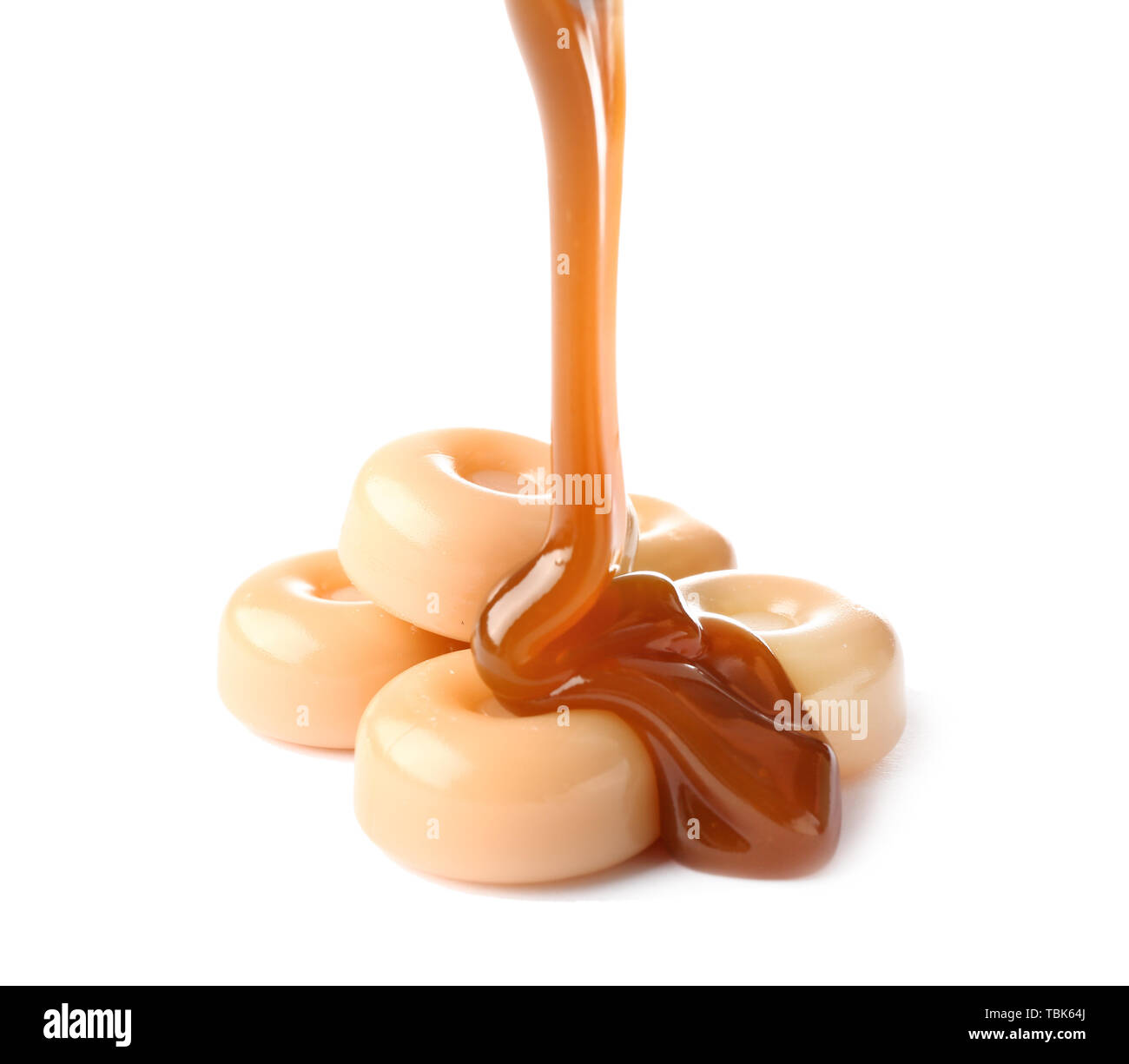 Pouring of liquid caramel onto candies on white background Stock Photo ...
