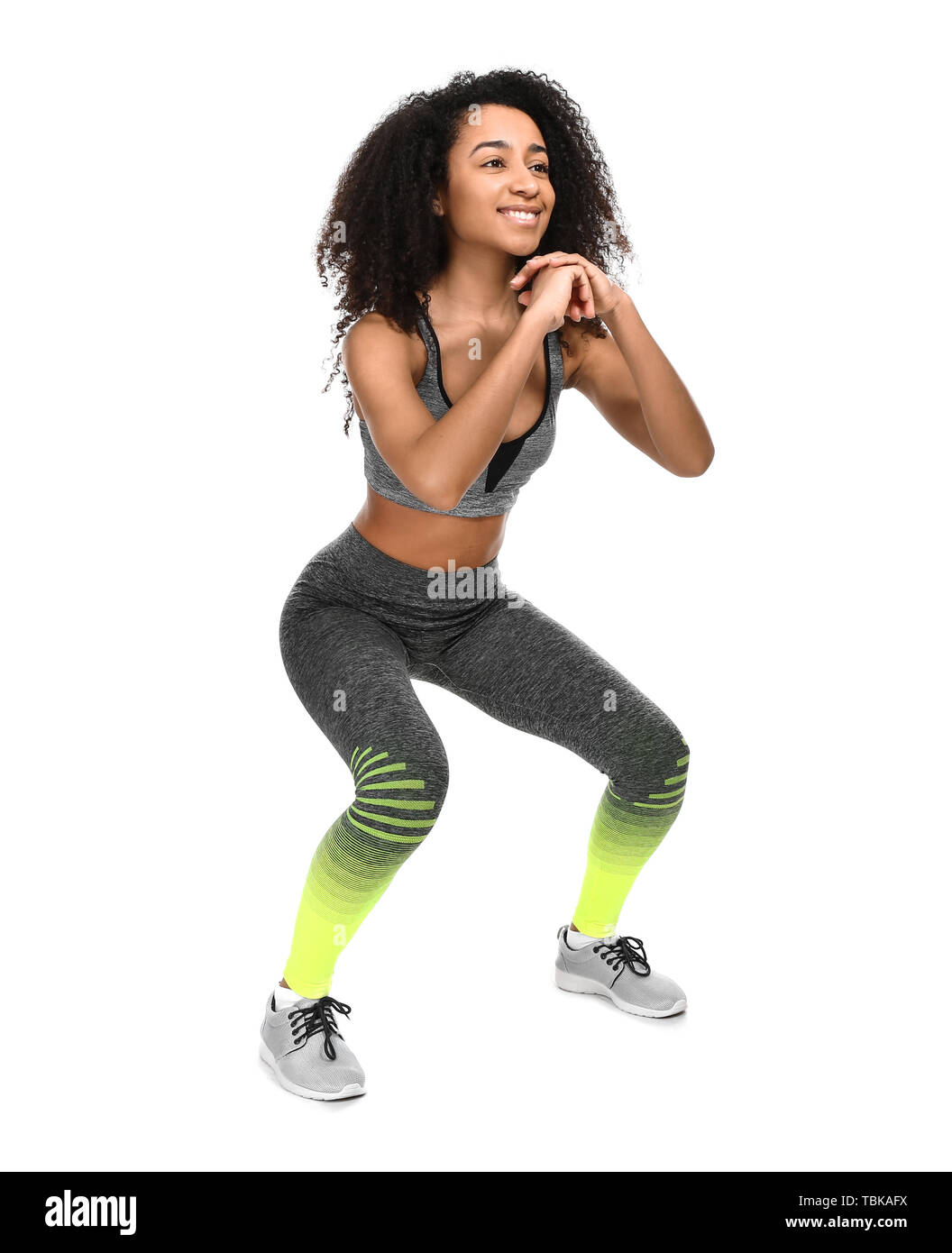 Sporty African-American woman doing squats on white background Stock ...