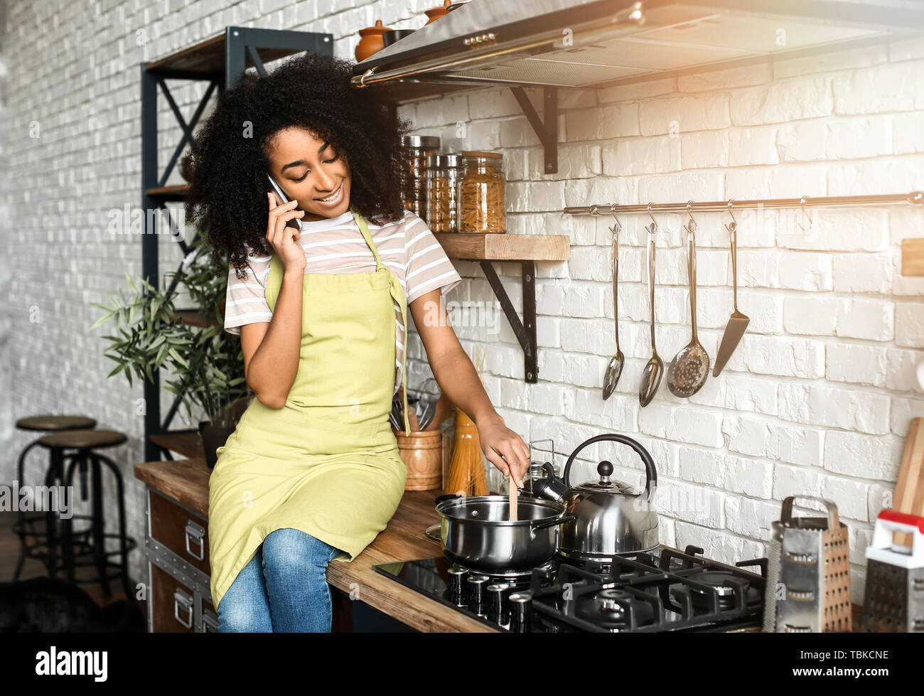 African-American woman talking by phone while cooking in kitchen Stock ...