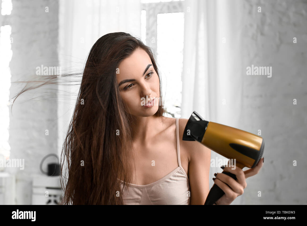 Beautiful young woman drying her healthy long hair at home Stock Photo ...