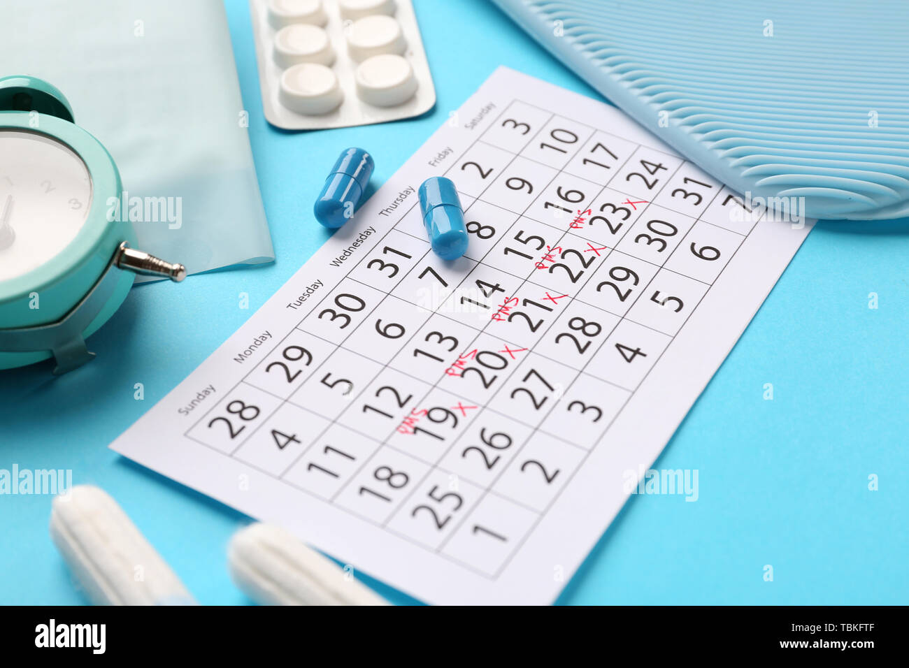 Menstrual calendar with feminine products and pills on color background ...