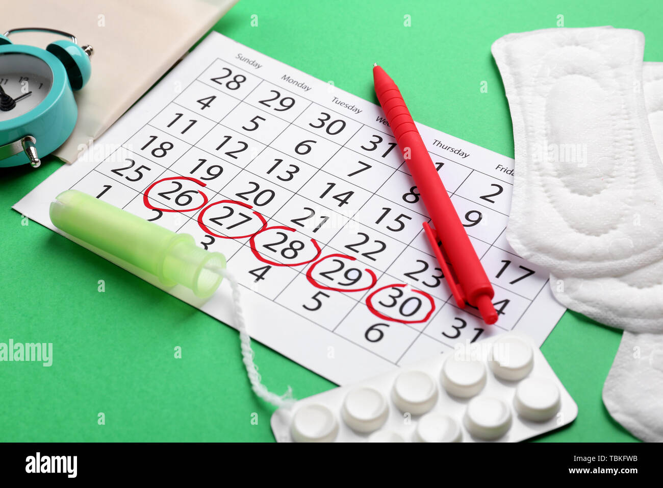 Menstrual calendar with feminine products and pills on color background ...