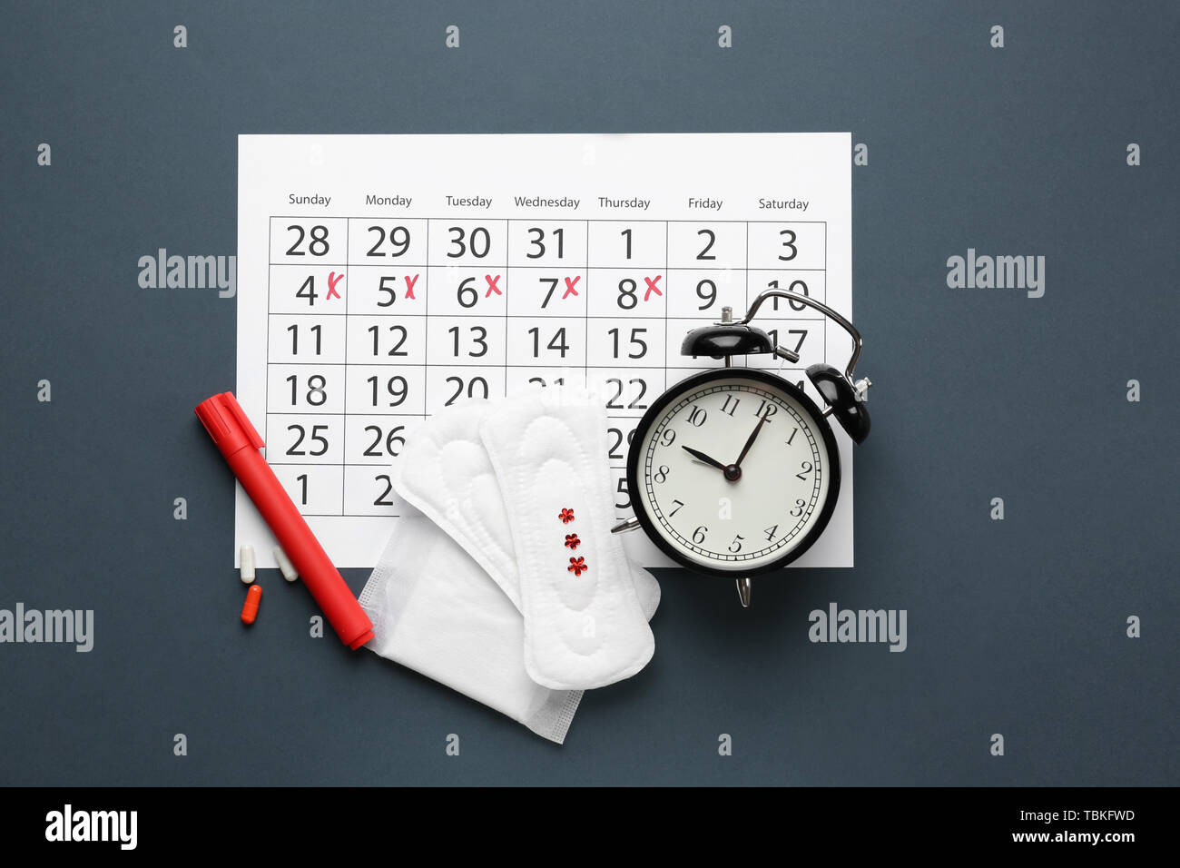Menstrual calendar with pads and alarm clock on dark background Stock ...