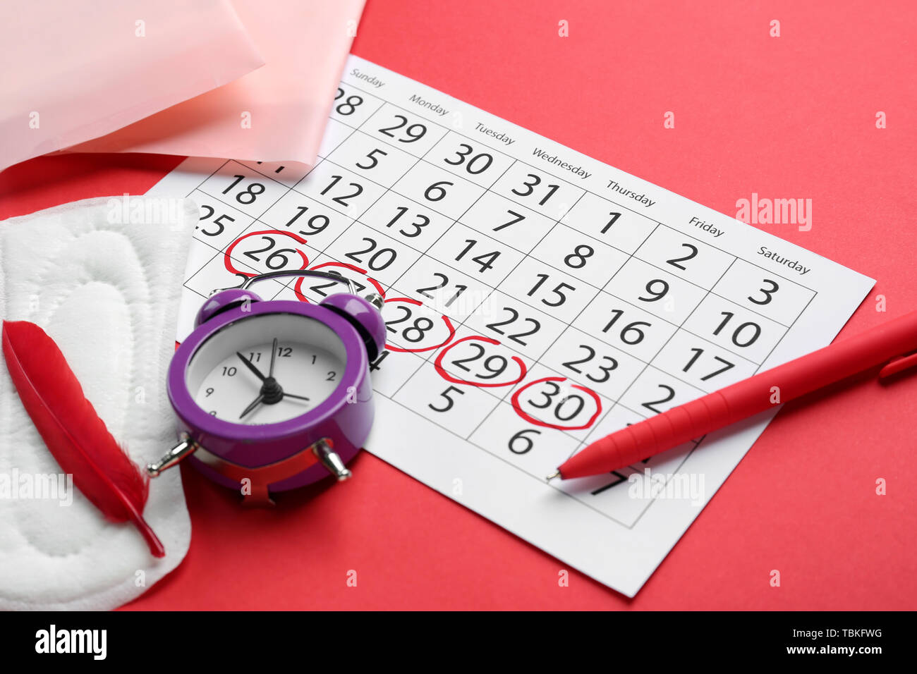 Menstrual calendar with feminine products and alarm clock on color ...