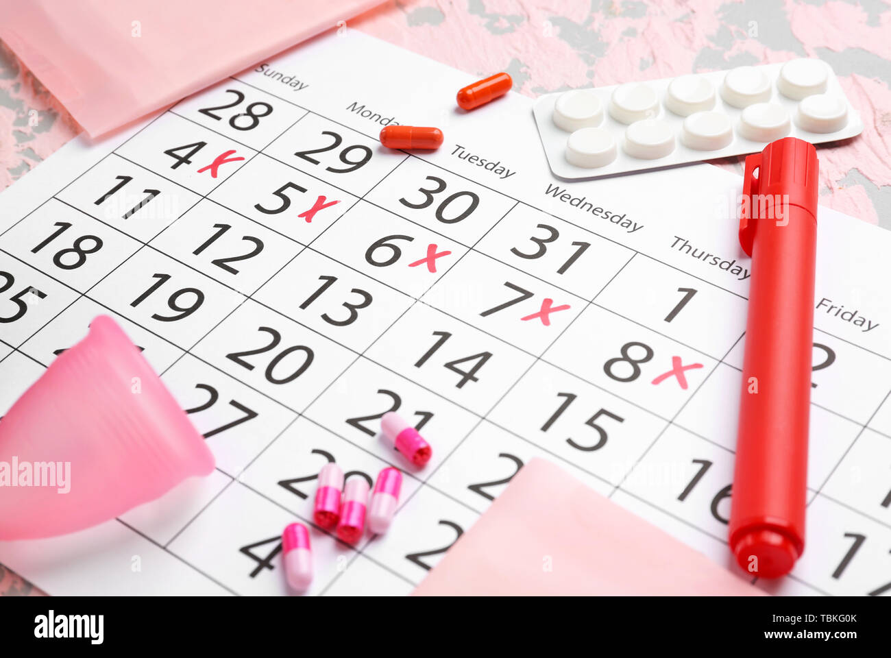 Menstrual calendar with feminine products and pills on color background ...