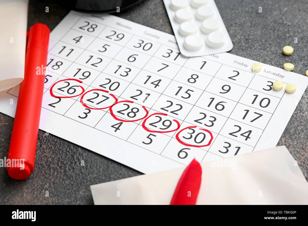 Menstrual calendar with feminine products and pills on grey background ...