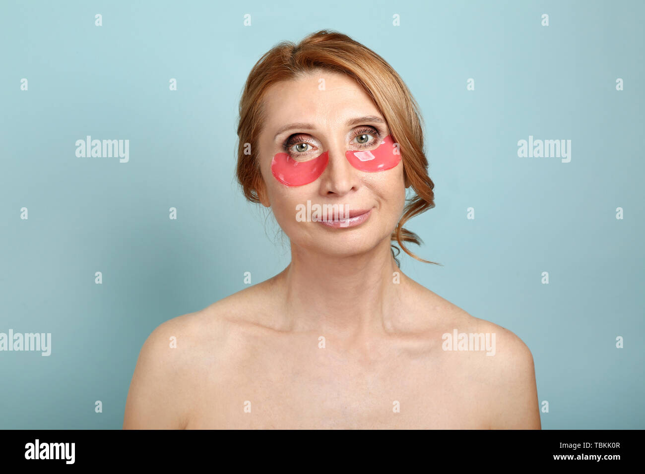 Mature woman with under-eye patches on color background Stock Photo - Alamy