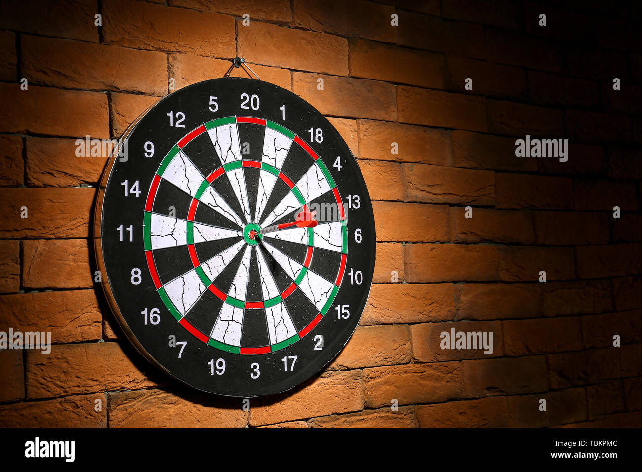 Dartboard with hit bullseye on brick wall Stock Photo - Alamy