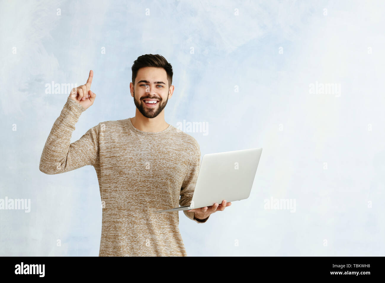 Male programmer with laptop and raised index finger on color background ...