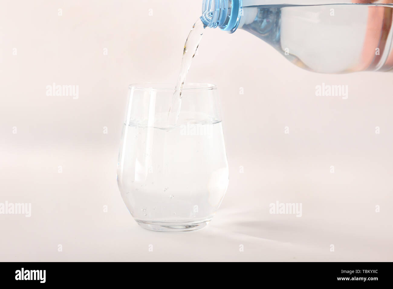 Pouring of water into glass on white background Stock Photo - Alamy