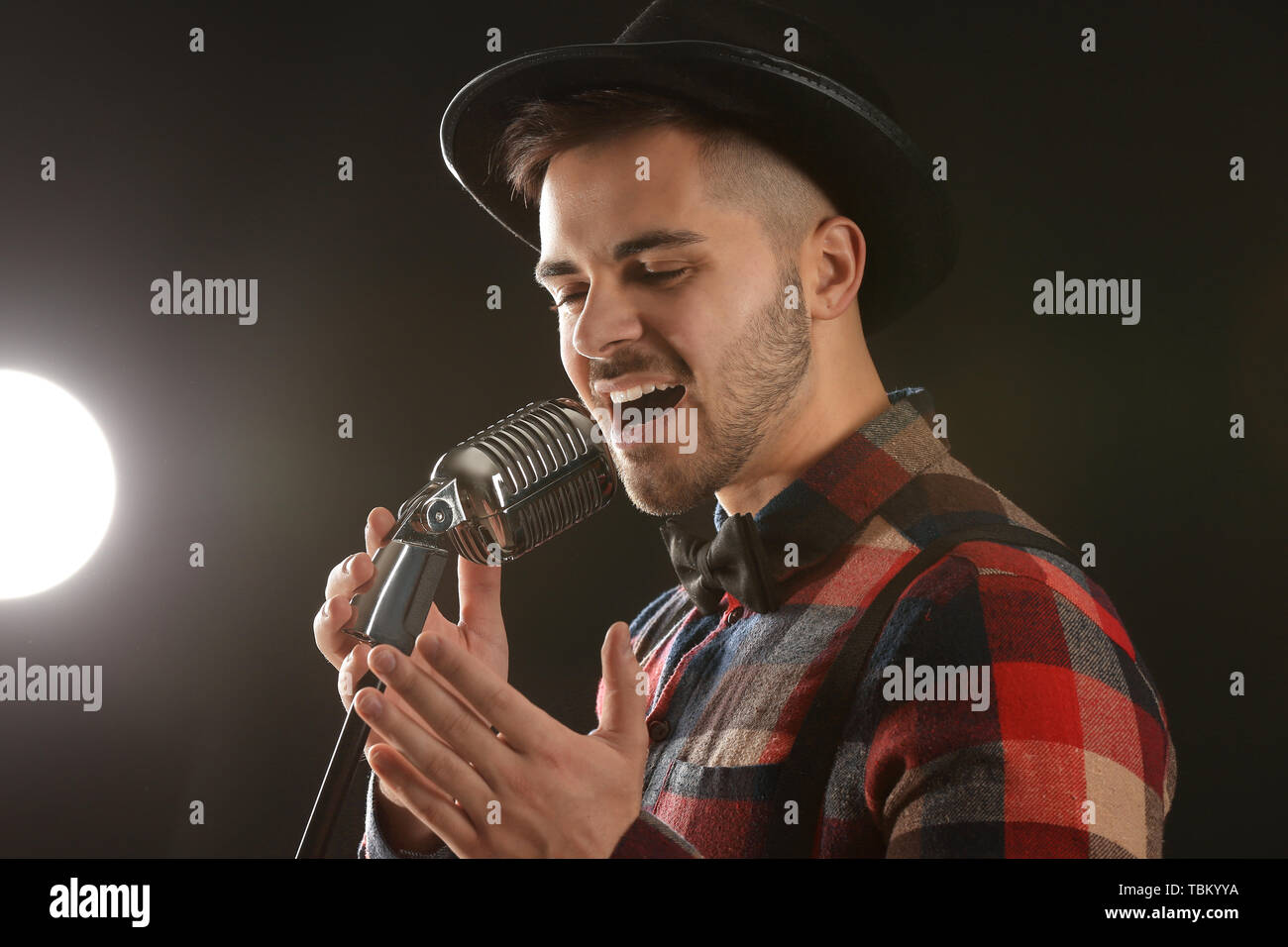 Handsome male singer with microphone on stage Stock Photo - Alamy