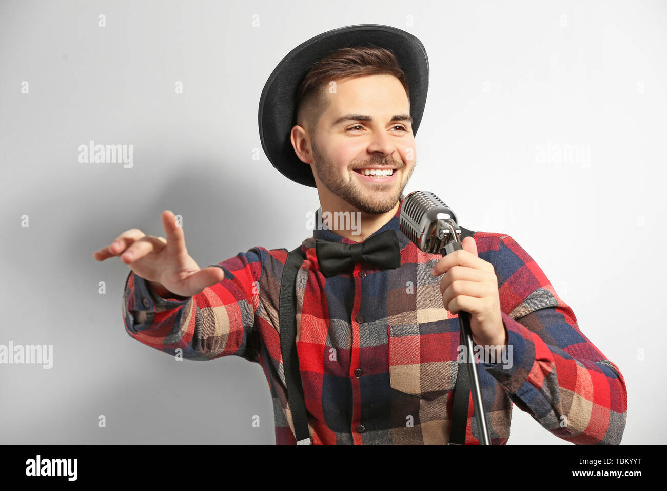 Handsome male singer with microphone on light background Stock Photo ...