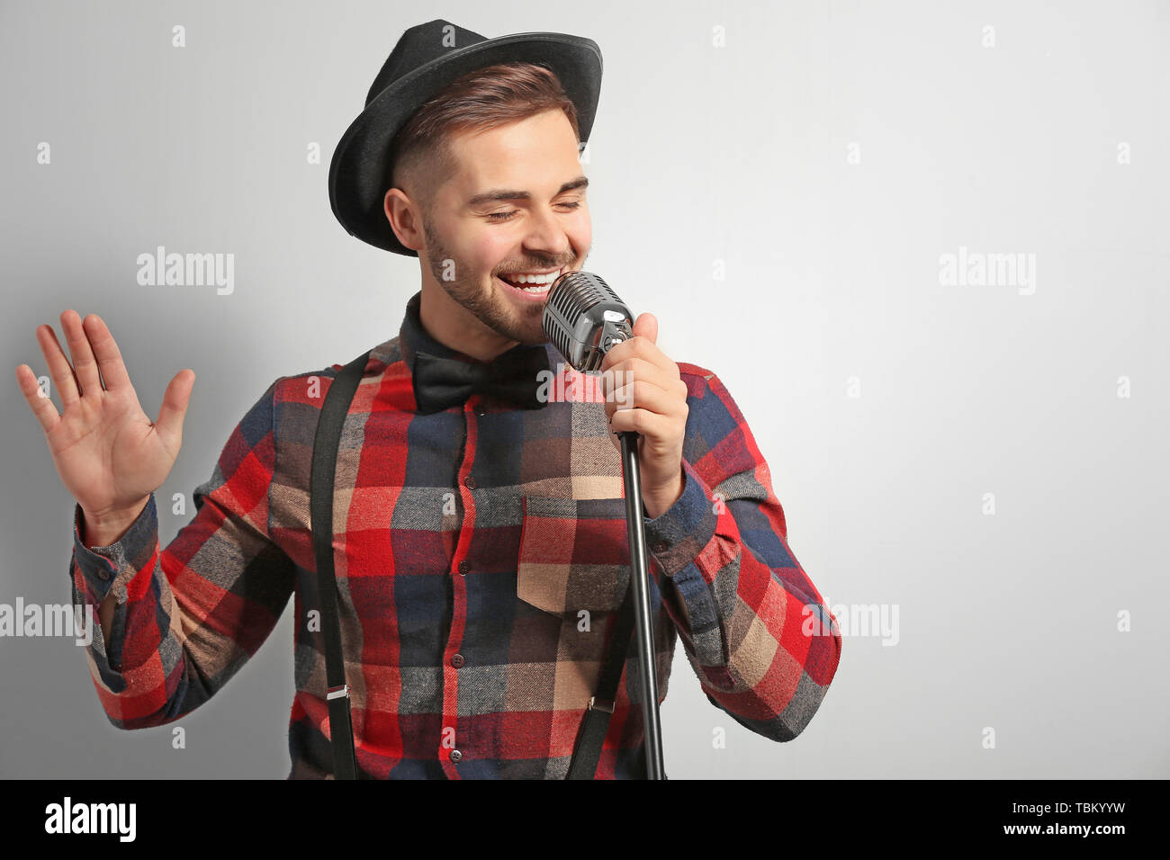Handsome male singer with microphone on light background Stock Photo ...