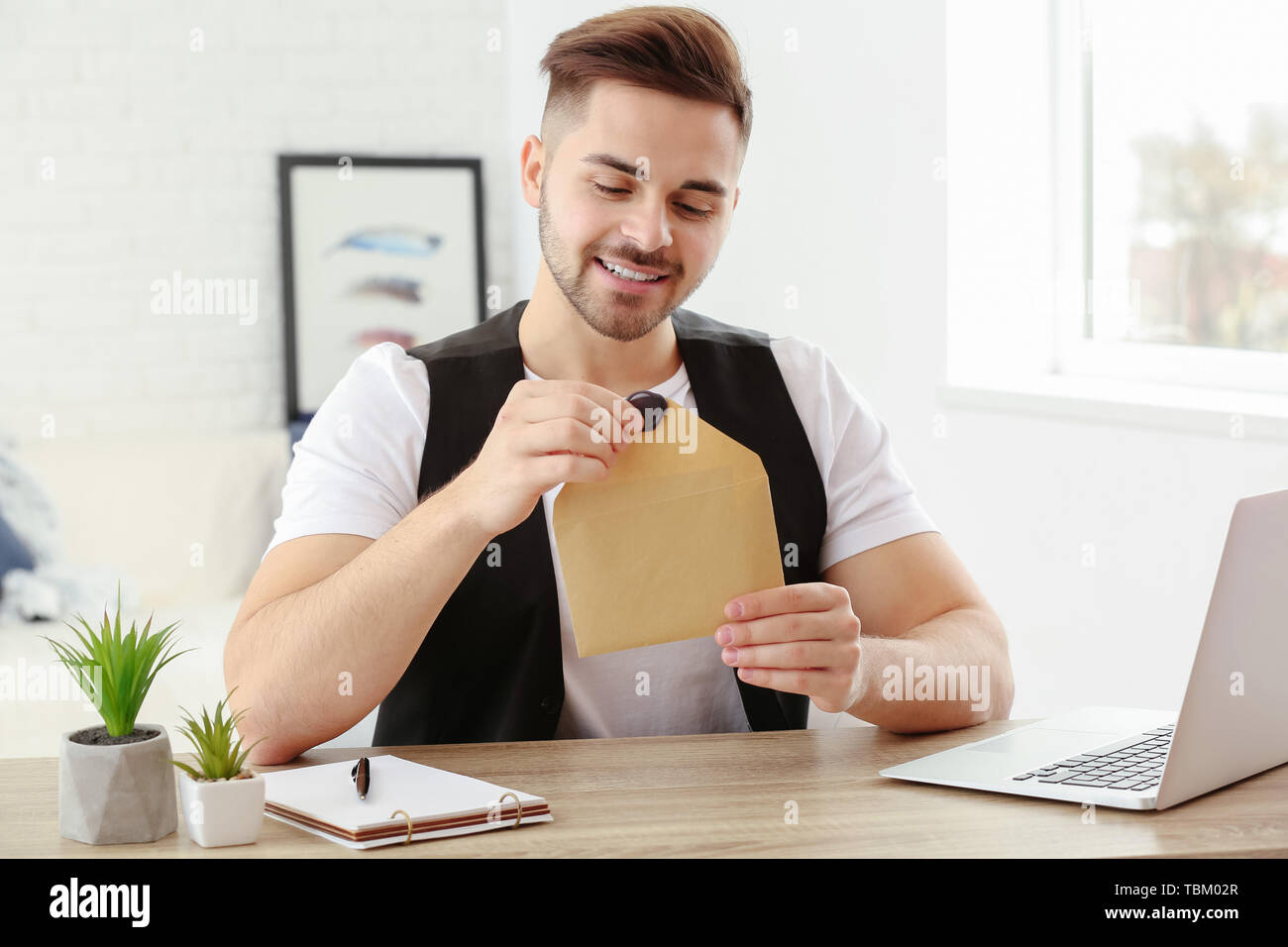 Young man opening envelope with invitation at home Stock Photo - Alamy