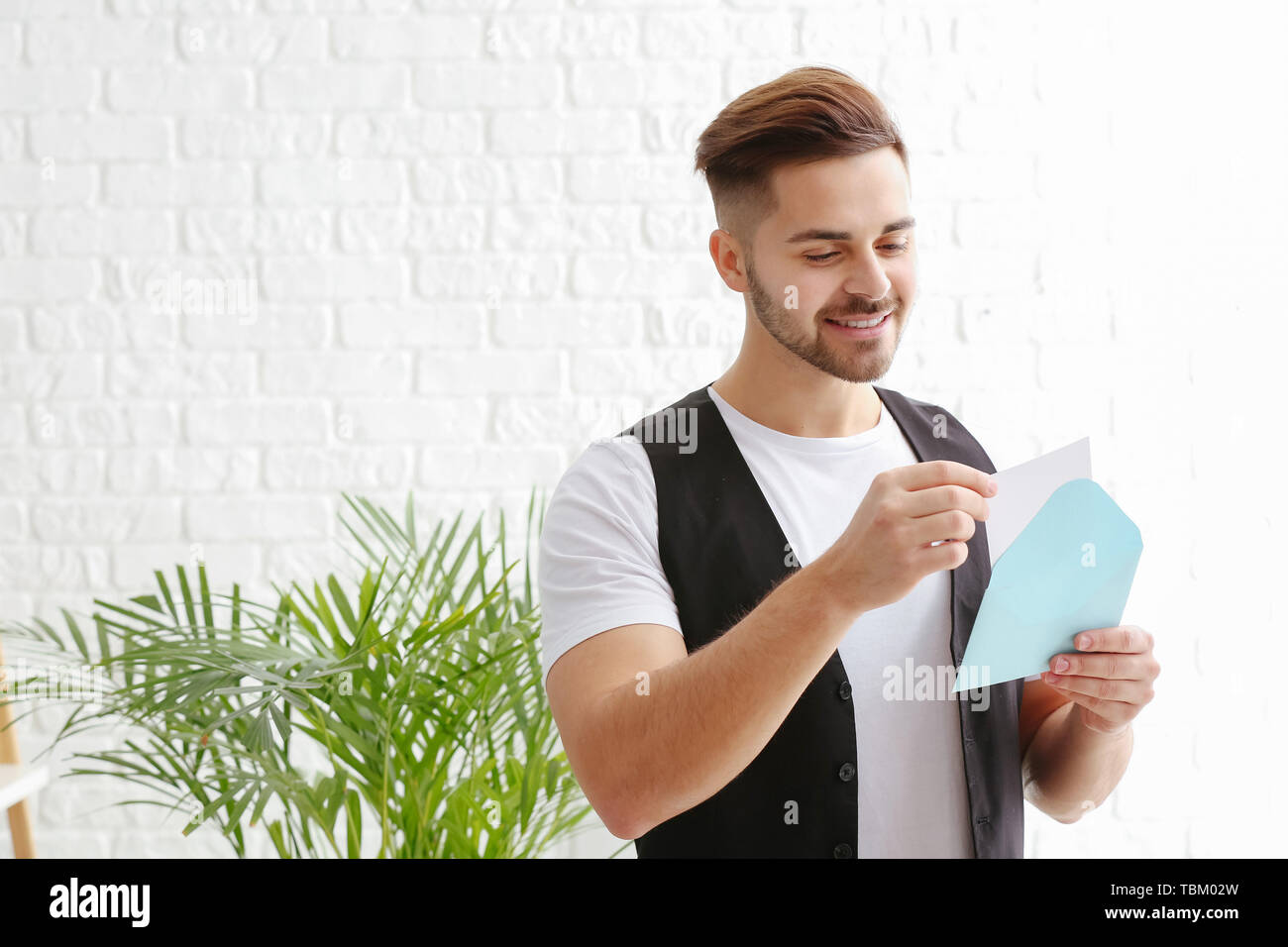 Young man opening envelope with invitation at home Stock Photo - Alamy