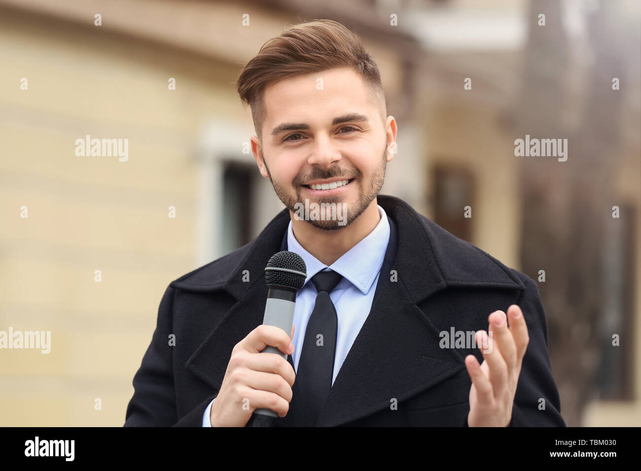 Handsome reporter with microphone outdoors Stock Photo - Alamy