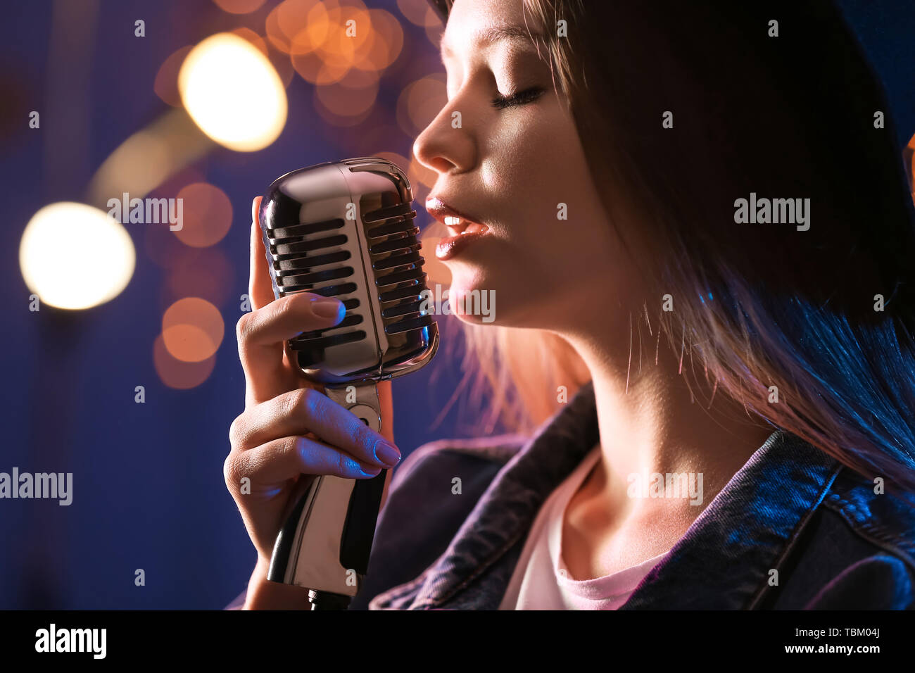 Beautiful female singer with microphone on stage Stock Photo - Alamy