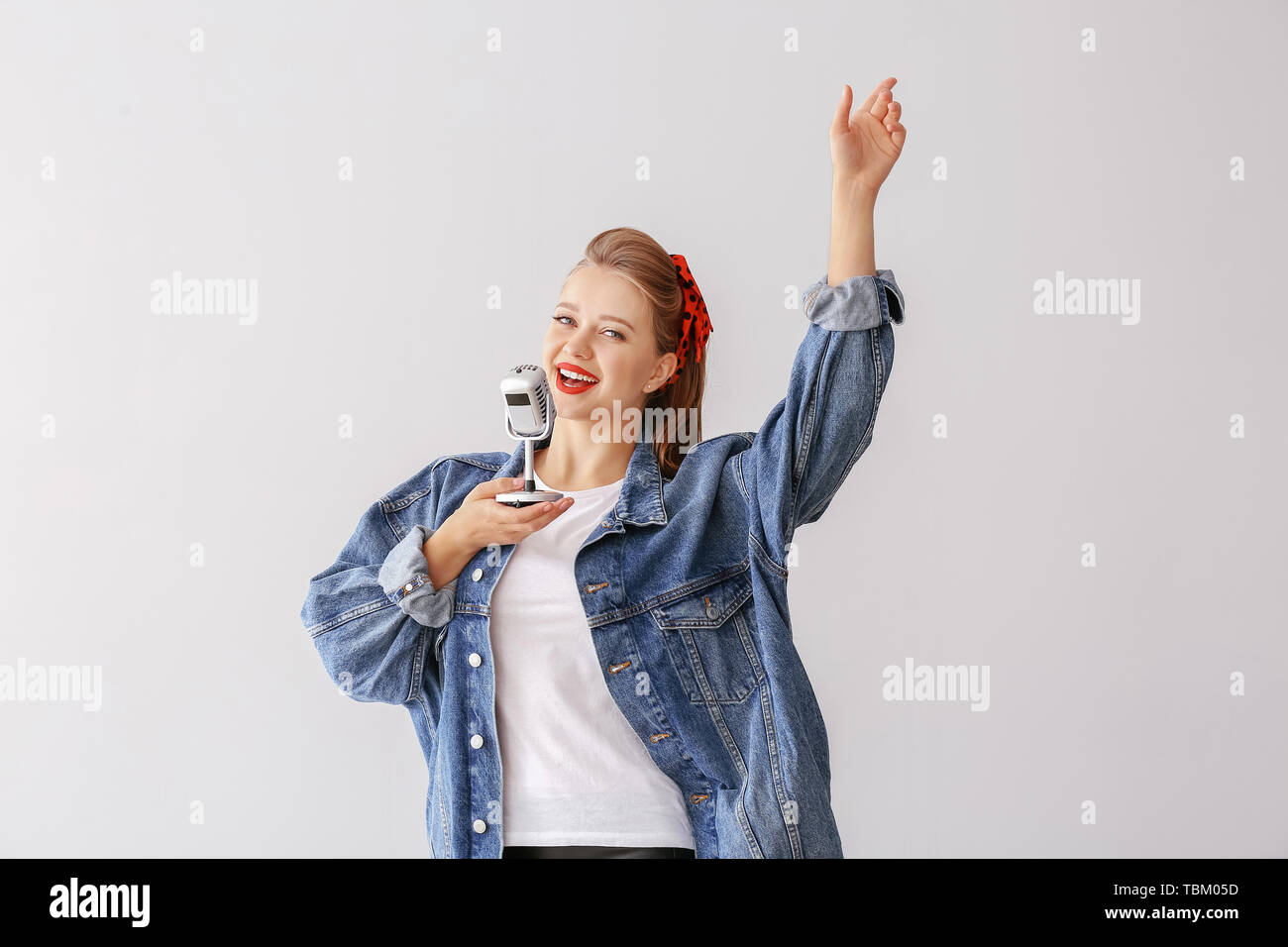 Beautiful female singer with microphone on light background Stock Photo ...