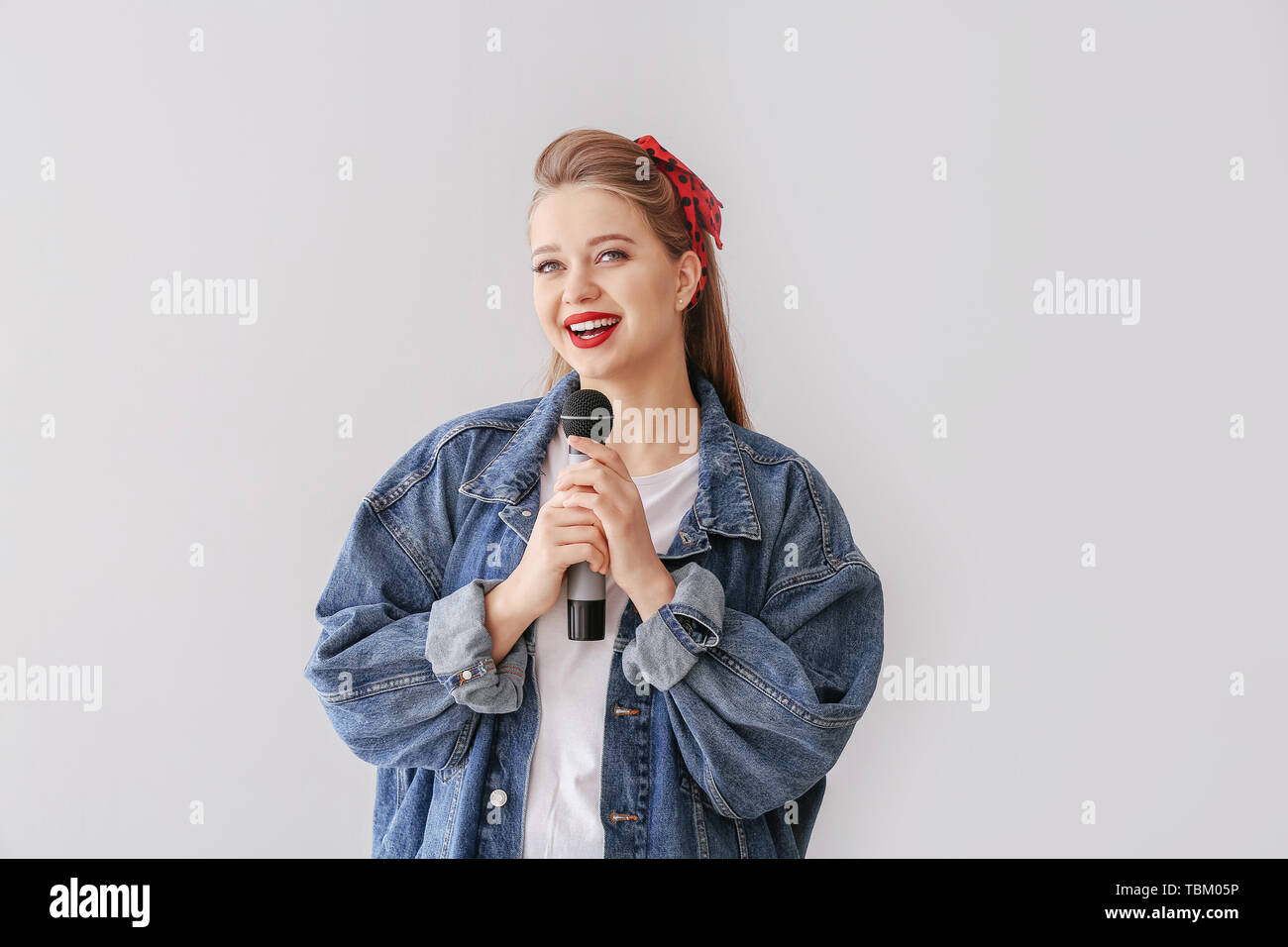 Beautiful female singer with microphone on light background Stock Photo ...