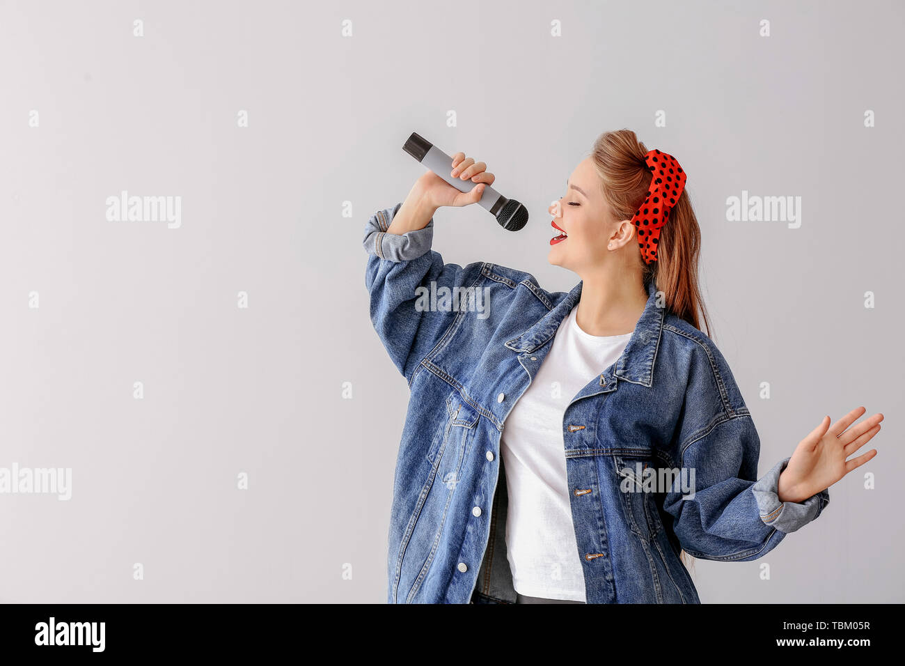 Beautiful female singer with microphone on light background Stock Photo ...